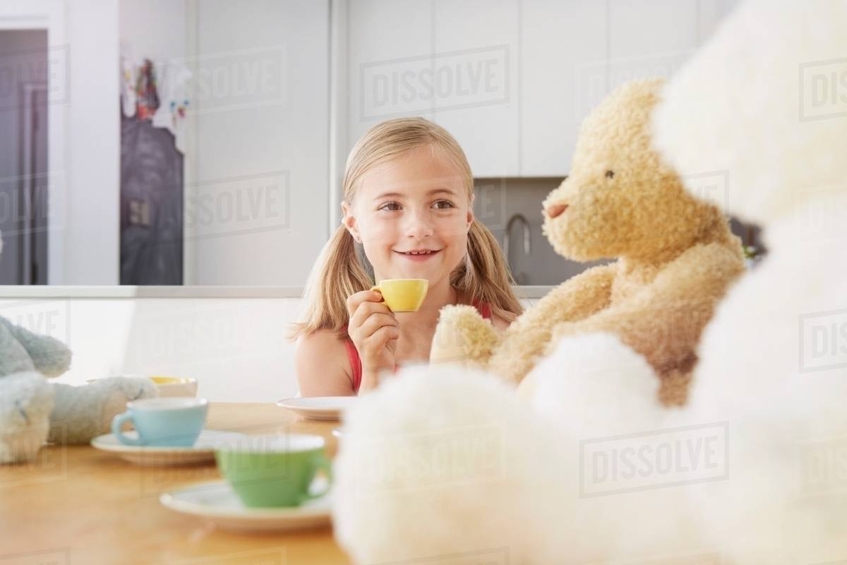 Girl having tea party with soft toys - Stock Photo - Dissolve