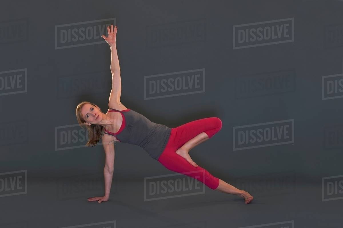 Woman in yoga pose on grey background - Stock Photo - Dissolve