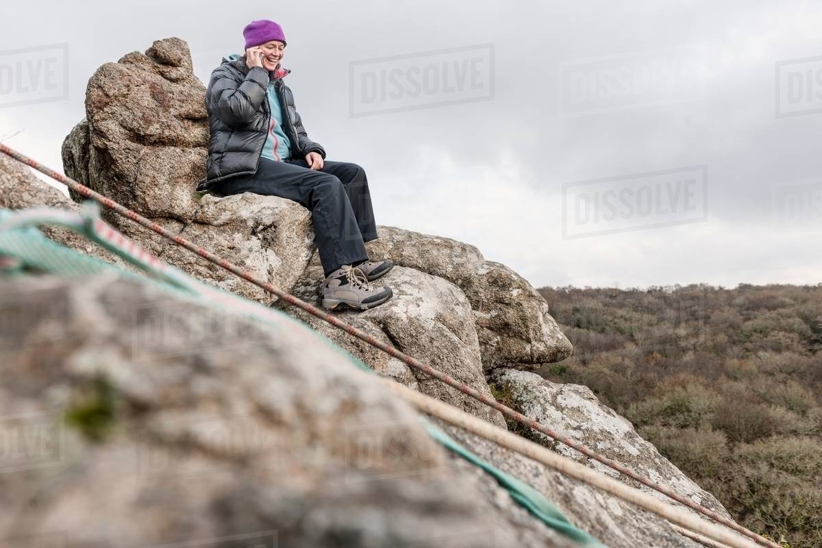 Female rock climber using cell phone - Stock Photo - Dissolve