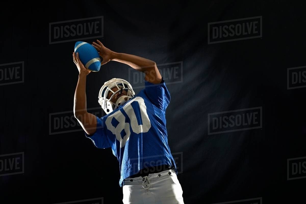 Studio shot of american footballer reaching for ball - Stock Photo ...