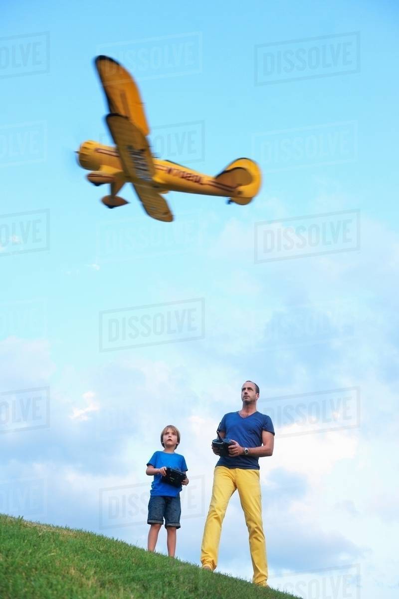 Father and son flying model plane - Stock Photo - Dissolve