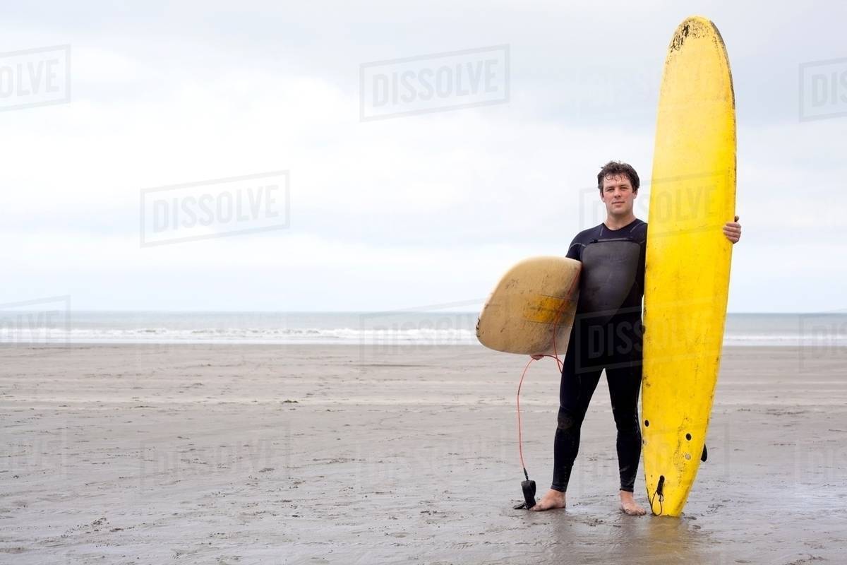 Portrait of man with surfboards on beach - Stock Photo - Dissolve