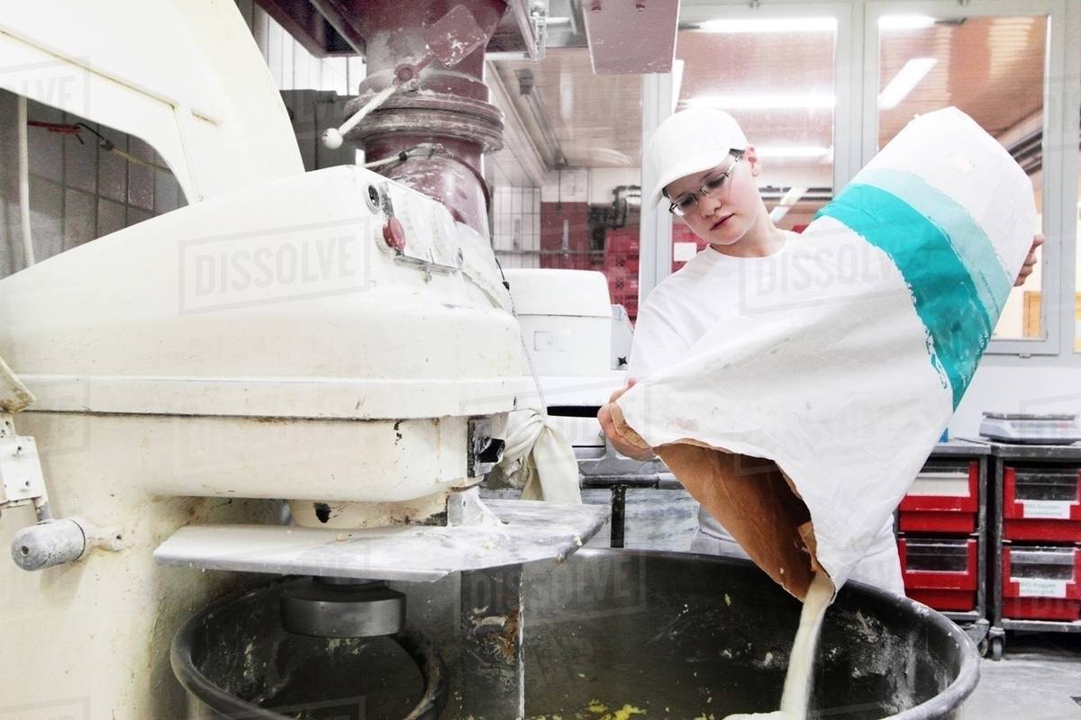 Baker pouring flour into mixer - Stock Photo - Dissolve