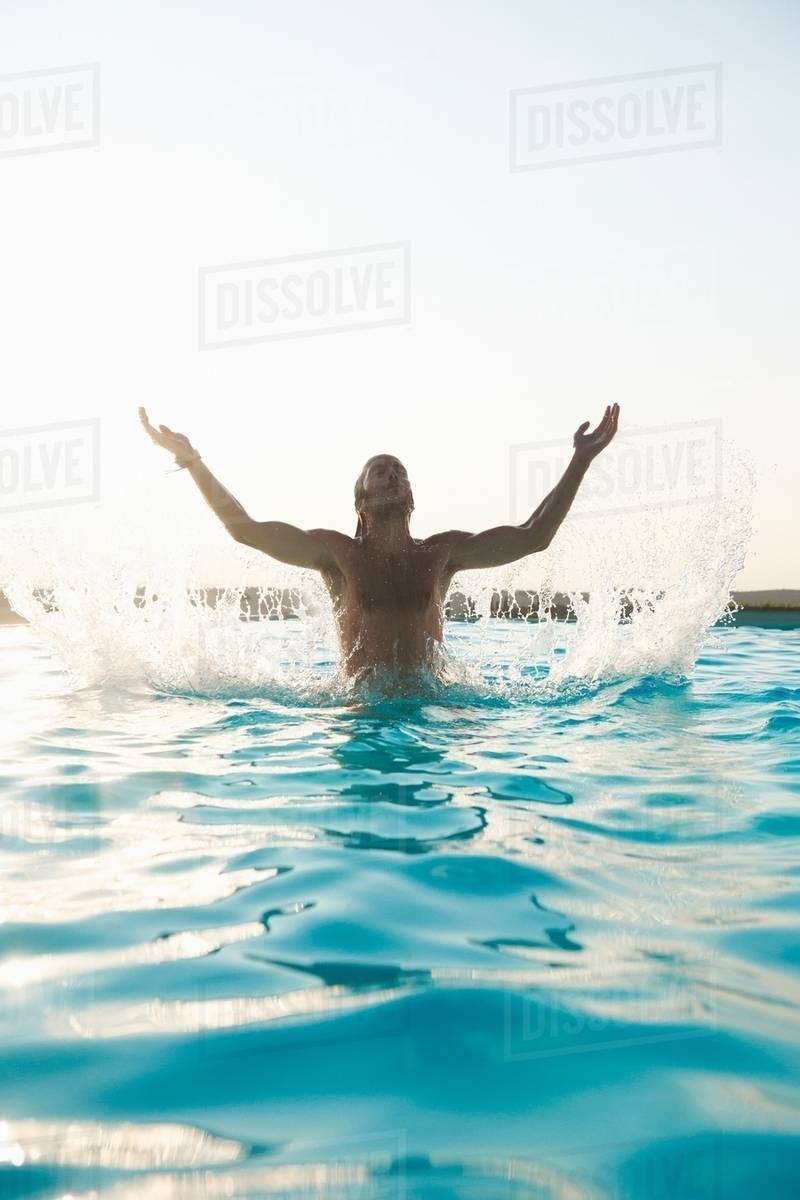 Man splashing water in outdoor swimming pool - Stock Photo - Dissolve