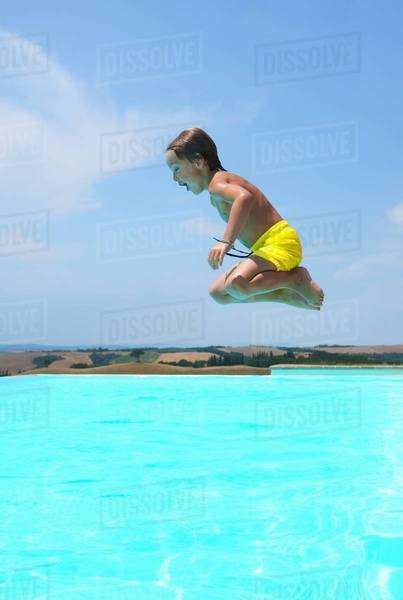 Boy jumping into swimming pool - Stock Photo - Dissolve