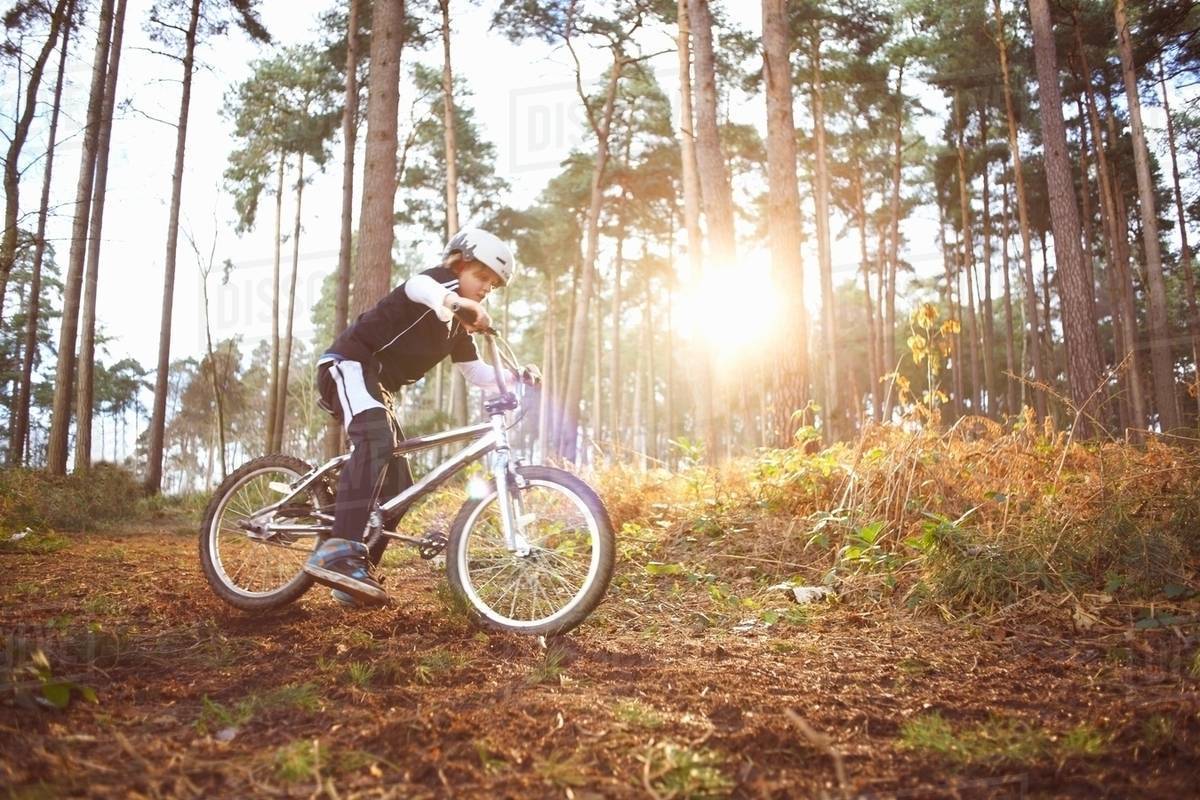 Boy riding his BMX through forest - Royalty-free Stock Photo | Dissolve