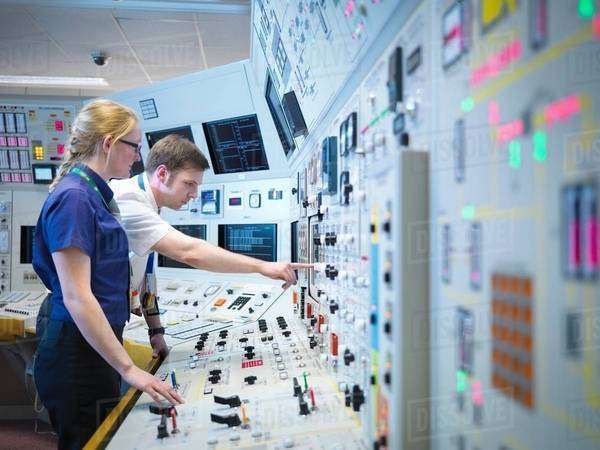 Female operator and trainee in nuclear power station control room ...