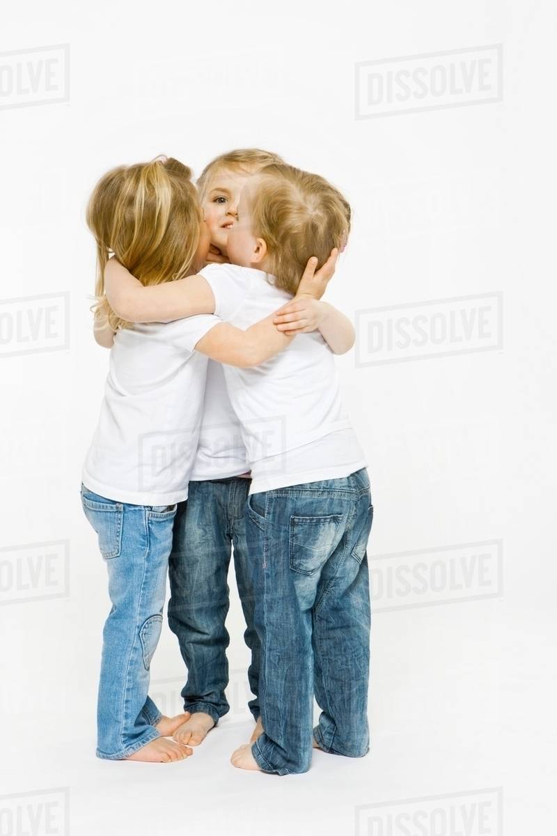 Three toddler girls hugging - Stock Photo - Dissolve