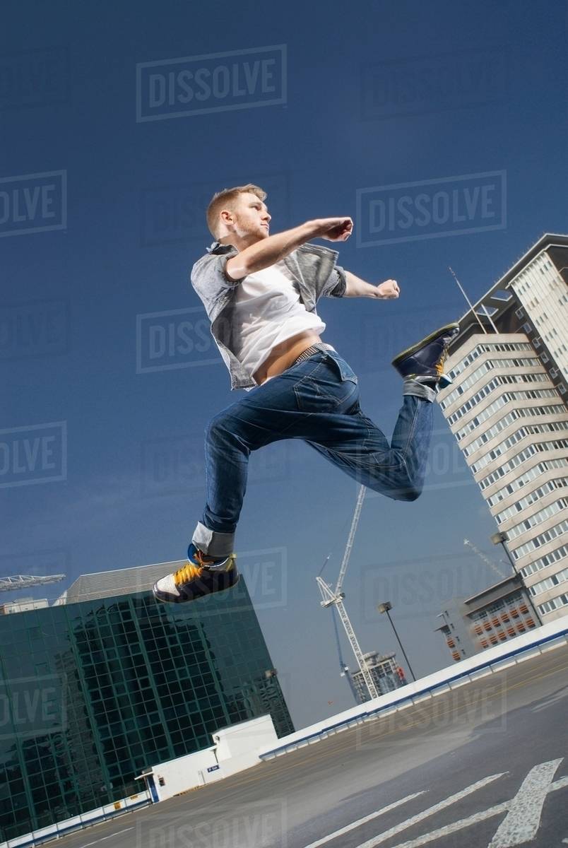 Man jumping on urban rooftop - Royalty-free Stock Photo | Dissolve