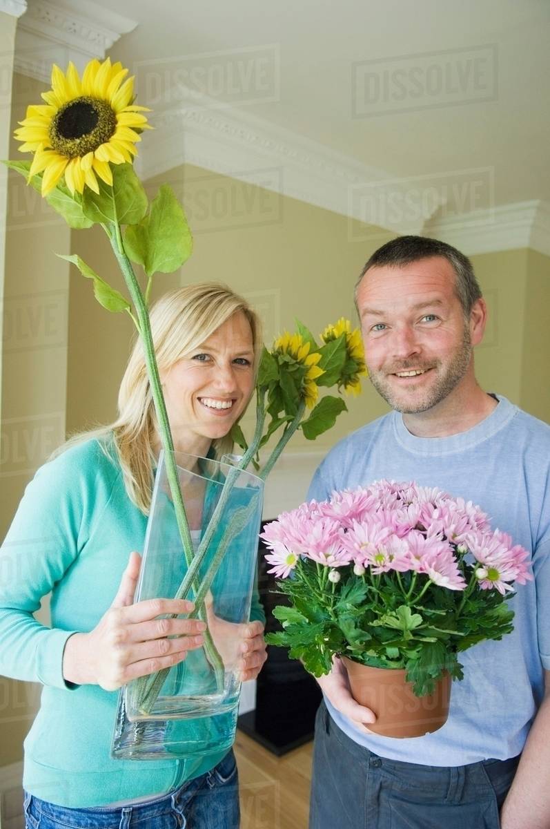 Couple carrying flowers in new home - Stock Photo - Dissolve