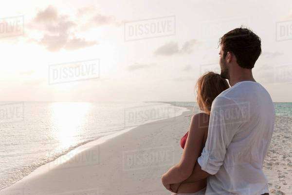 Couple admiring horizon at beach - Royalty-free Stock Photo | Dissolve
