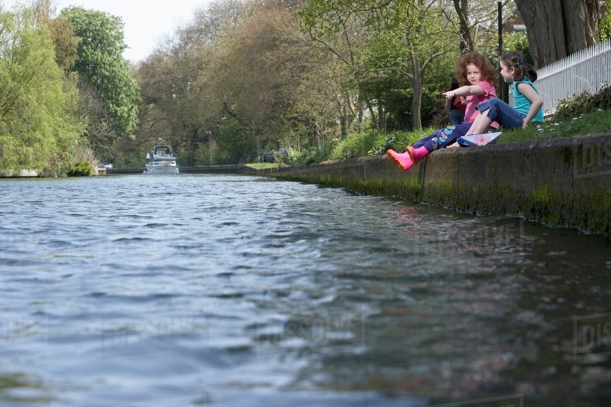 Girls sitting on riverbank together - Royalty-free Stock Photo | Dissolve