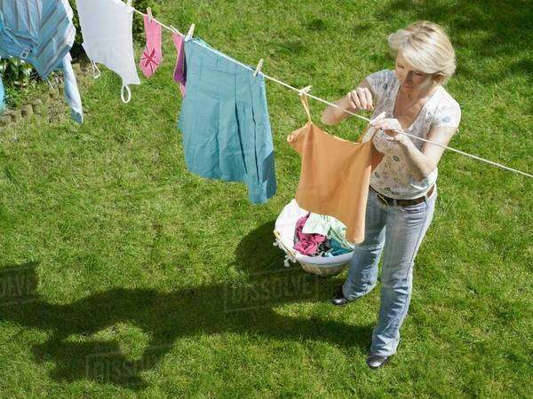 Woman hanging clothes on clothesline - Stock Photo - Dissolve