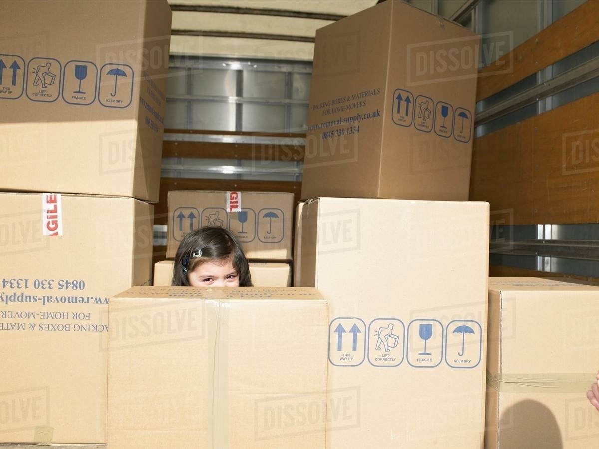 Girl hiding in boxes in moving van - Stock Photo - Dissolve