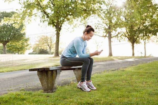 Runner using cell phone in park - Stock Photo - Dissolve