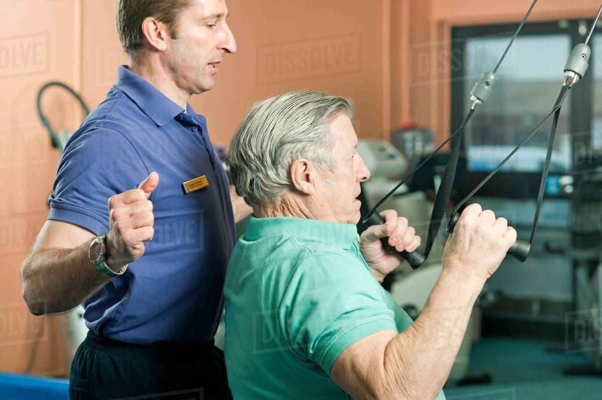 Trainer helping older man exercise - Royalty-free Stock Photo | Dissolve