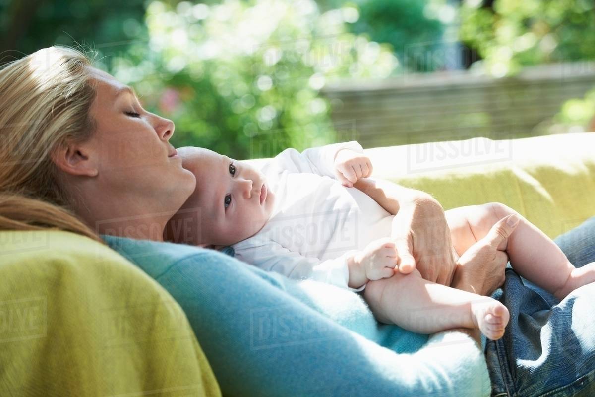 Smiling mother relaxing with baby - Stock Photo - Dissolve
