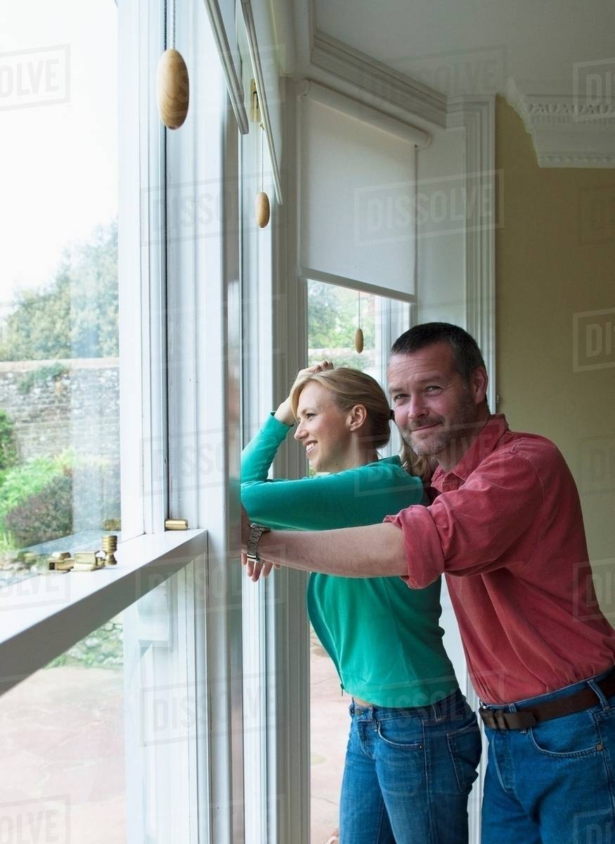 Couple standing by window together - Stock Photo - Dissolve