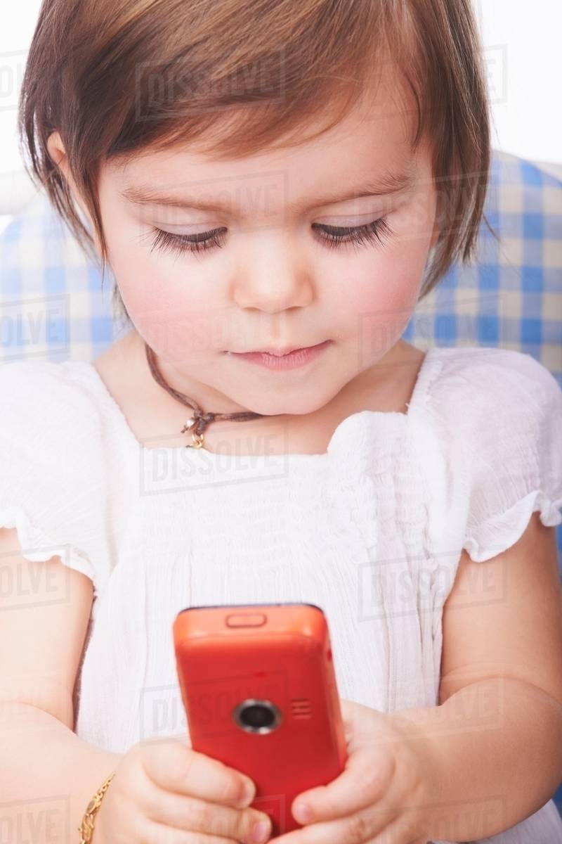 Baby girl playing with cell phone - Stock Photo - Dissolve