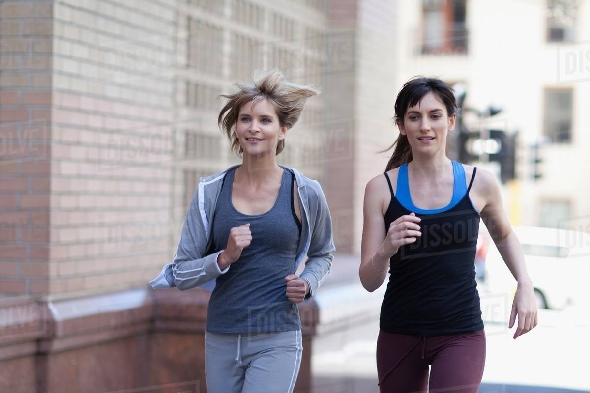Women running together on city street - Stock Photo - Dissolve