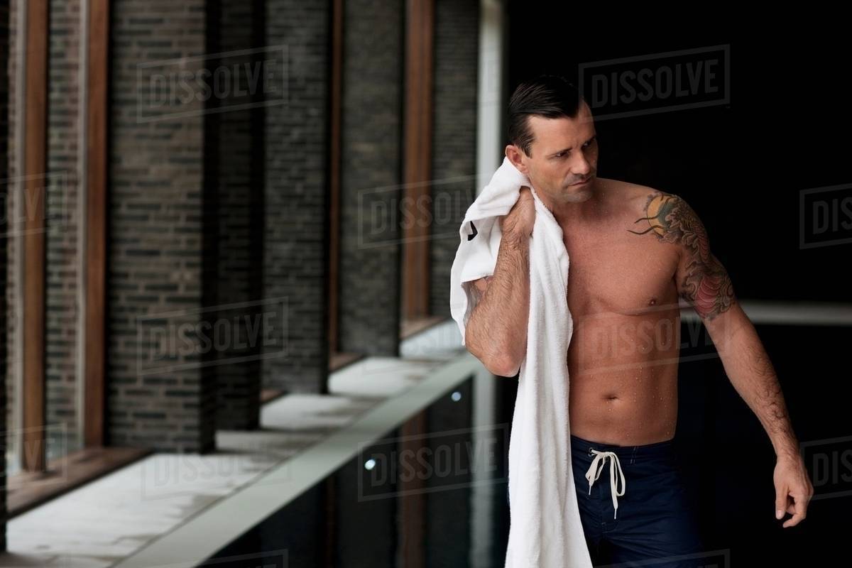 Man drying off by indoor pool - Royalty-free Stock Photo | Dissolve