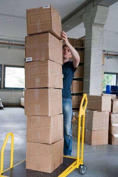Man stacking cardboard boxes on dolly - Stock Photo - Dissolve