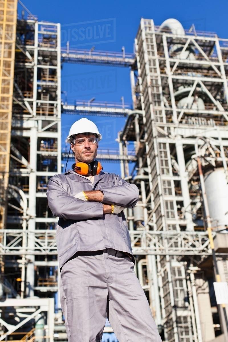 Worker standing at oil refinery - Stock Photo - Dissolve