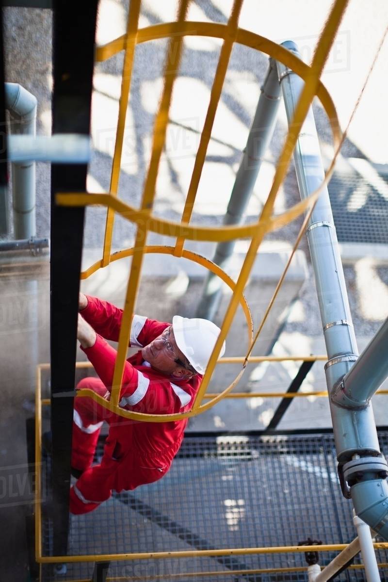 Worker climbing ladder at oil refinery - Royalty-free Stock Photo ...