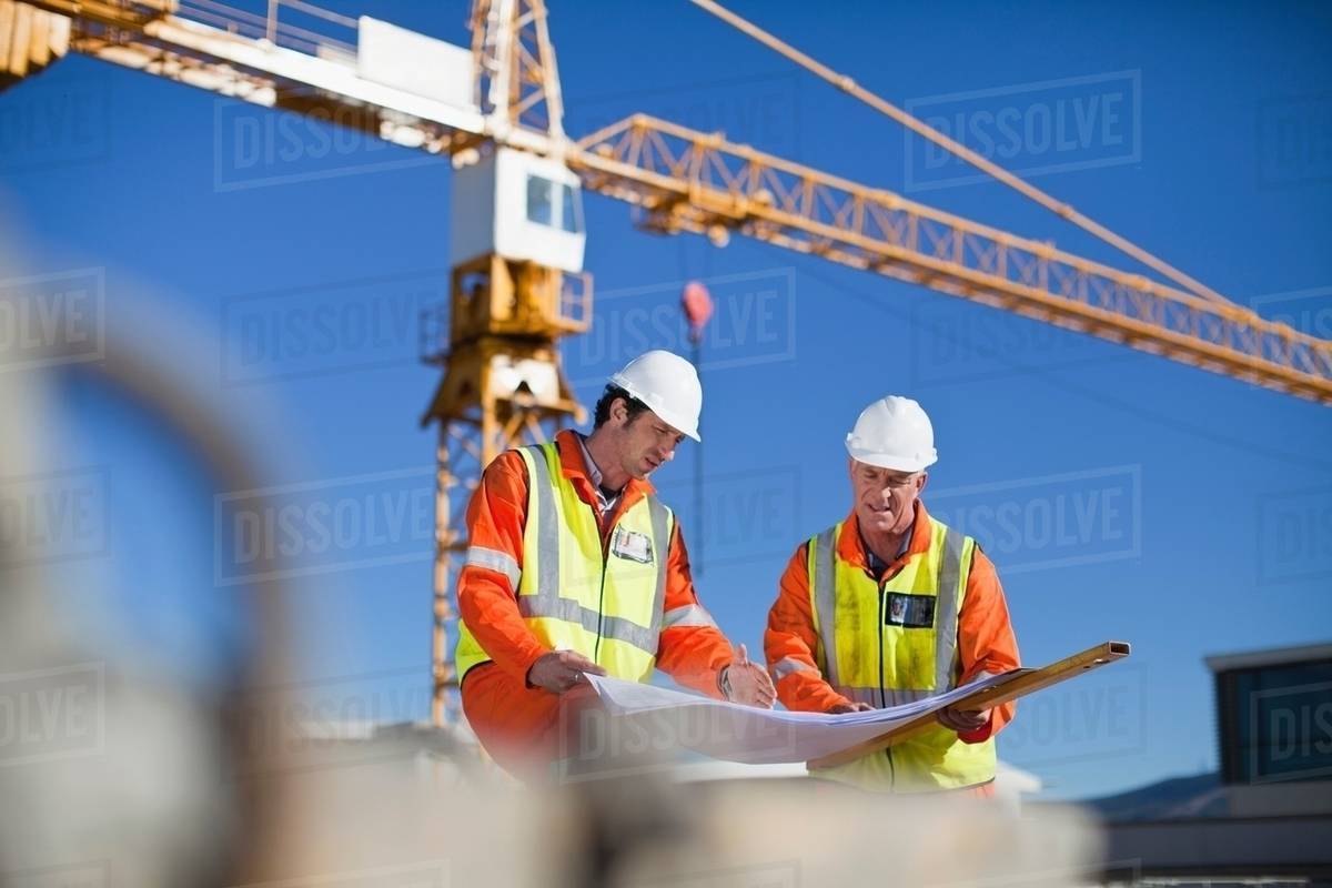 Workers reading blueprints on site - Stock Photo - Dissolve