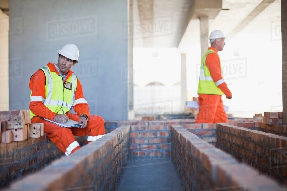 Worker writing on clipboard on site - Stock Photo - Dissolve