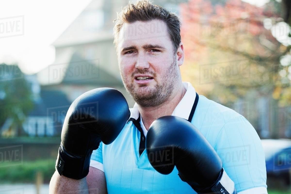 Boxer holding up gloves outdoors - Stock Photo - Dissolve