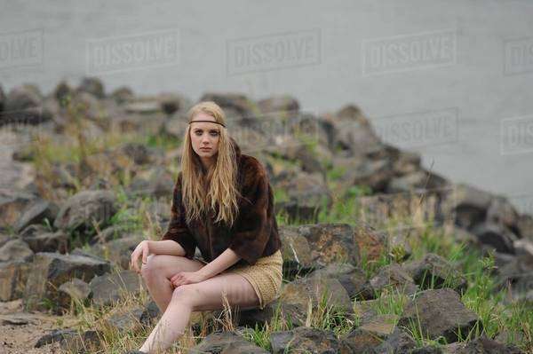 Teenage girl sitting on rocks - Stock Photo - Dissolve