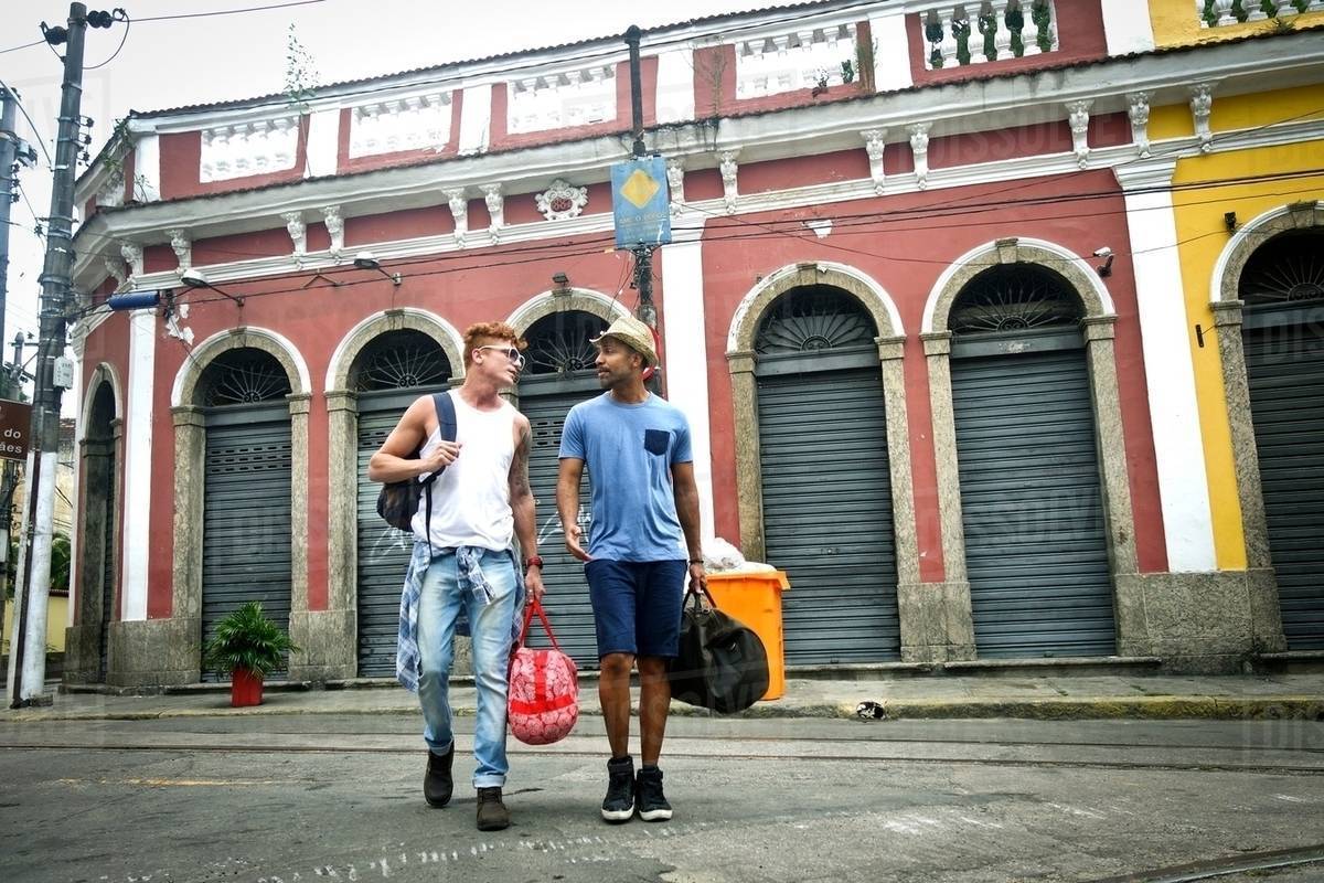 Two men walking together, carrying travel bags - Stock Photo - Dissolve