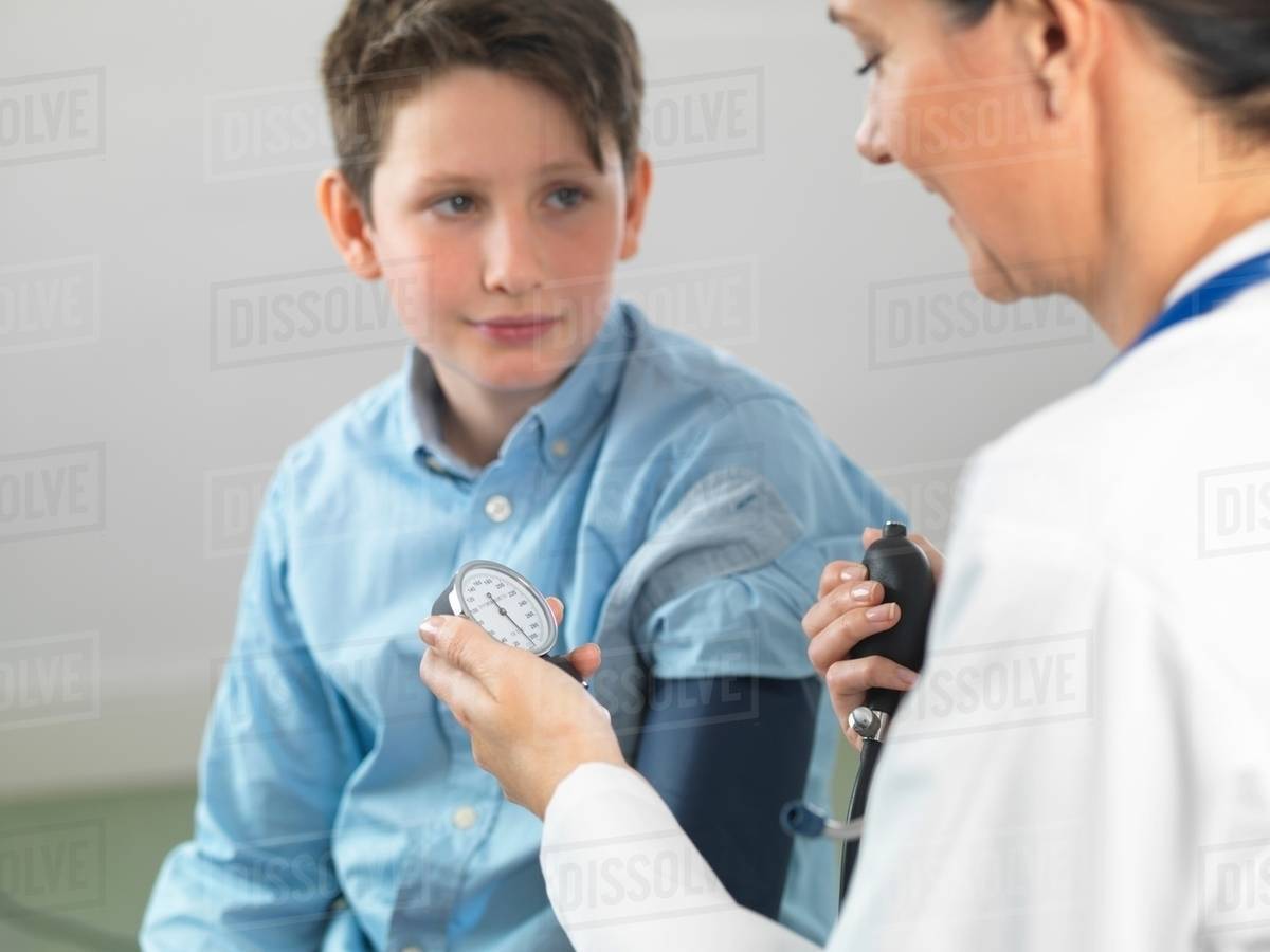 Doctor reading blood pressure of young boy in clinic - Royalty-free ...