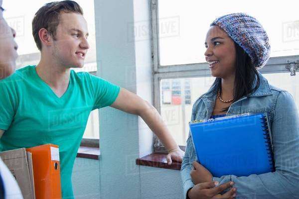 Students standing by window, chatting - Royalty-free Stock Photo | Dissolve