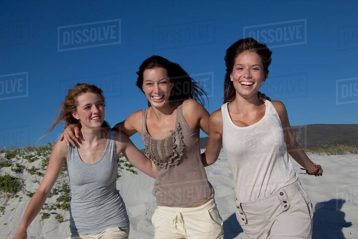Three girls smiling into camera - Stock Photo - Dissolve