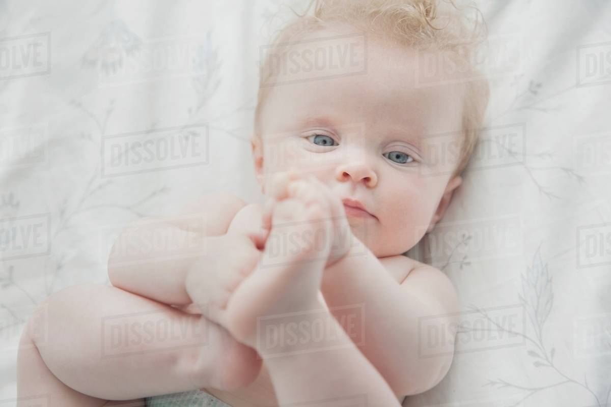 Baby Girl Lying On Back Holding Feet Stock Photo Dissolve baby-girl-lying-on-back-holding-feet-stock-photo-dissolve