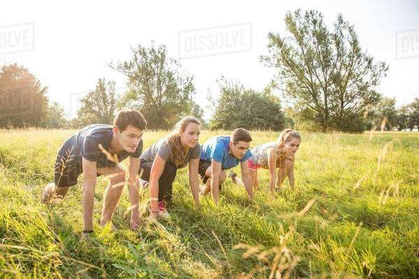 Group of friends in field, in starting position, about to race ...