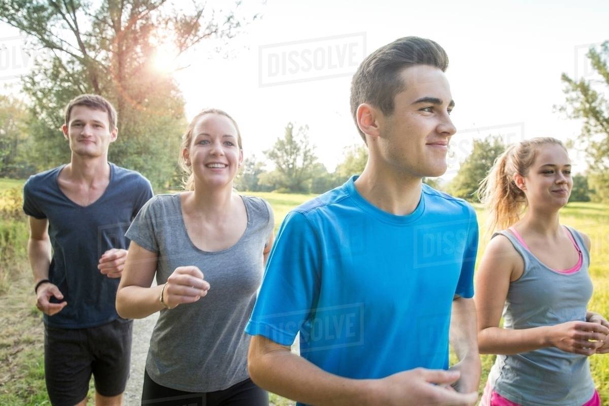 Group of friends running through field - Stock Photo - Dissolve