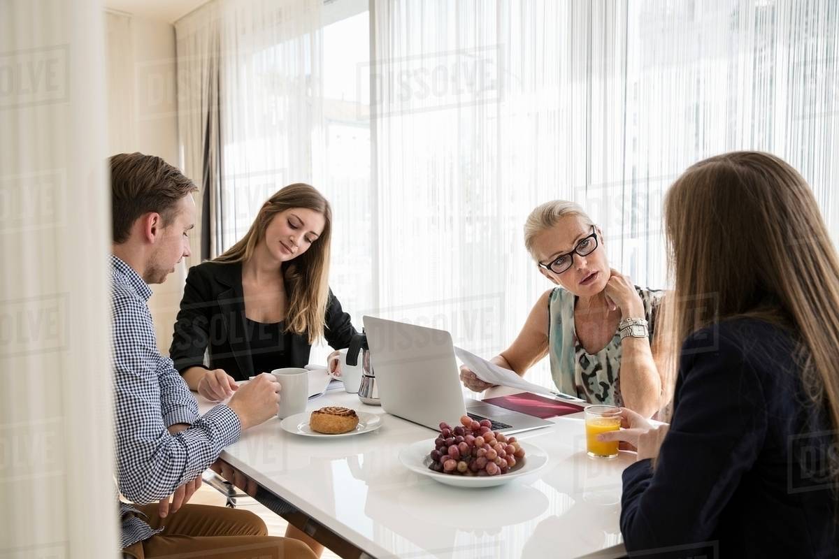 Colleagues sitting at table having business breakfast meeting - Royalty ...