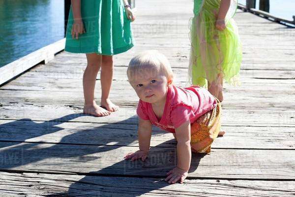 Portrait of female toddler crawling on pier, New Zealand - Stock Photo ...