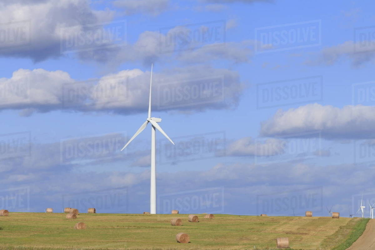 Kansas Electric Windmill in a Round Hay Bale field with blue sky and ...