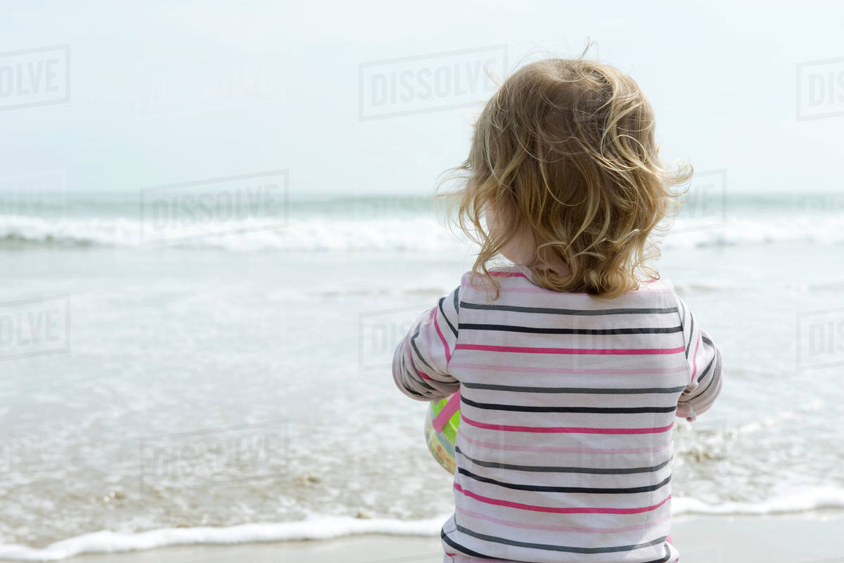Toddler at the beach, looking at ocean, rear view - Royalty-free Stock ...