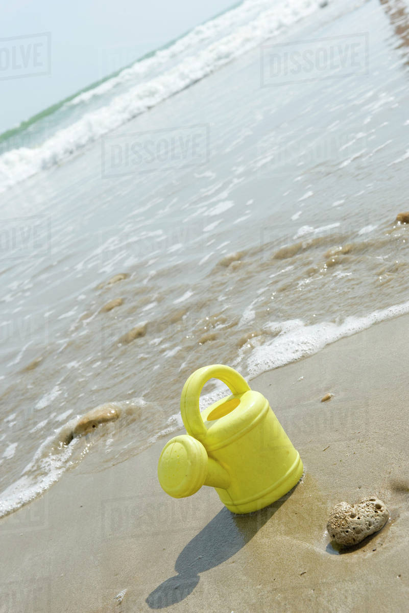 Toy watering can on beach - Royalty-free Stock Photo | Dissolve