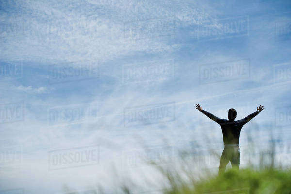 Man with arms up in nature, rear view - Stock Photo - Dissolve
