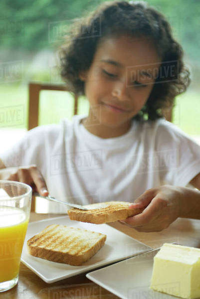 Girl buttering toast - Royalty-free Stock Photo | Dissolve