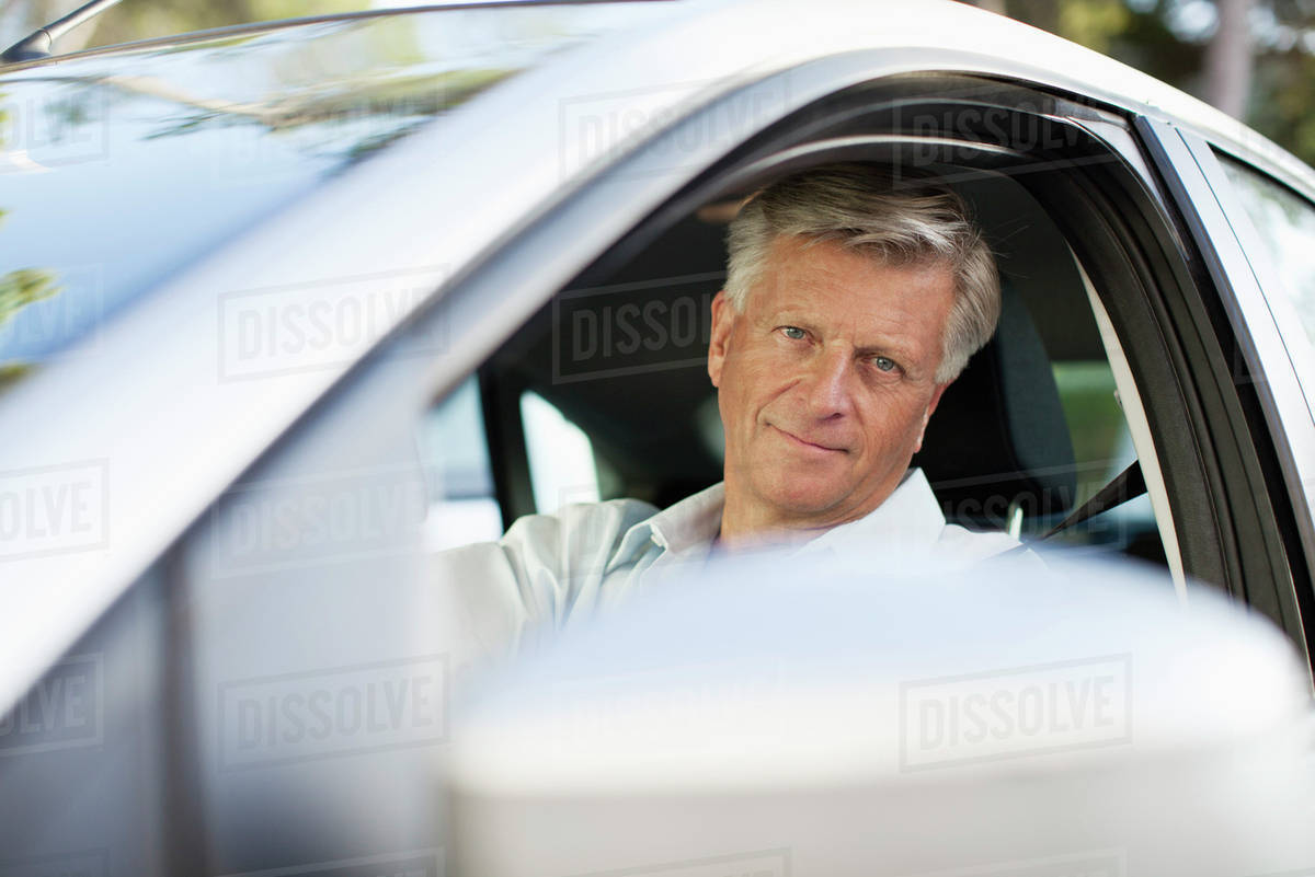 Man driving car, looking out window at camera - Stock Photo - Dissolve