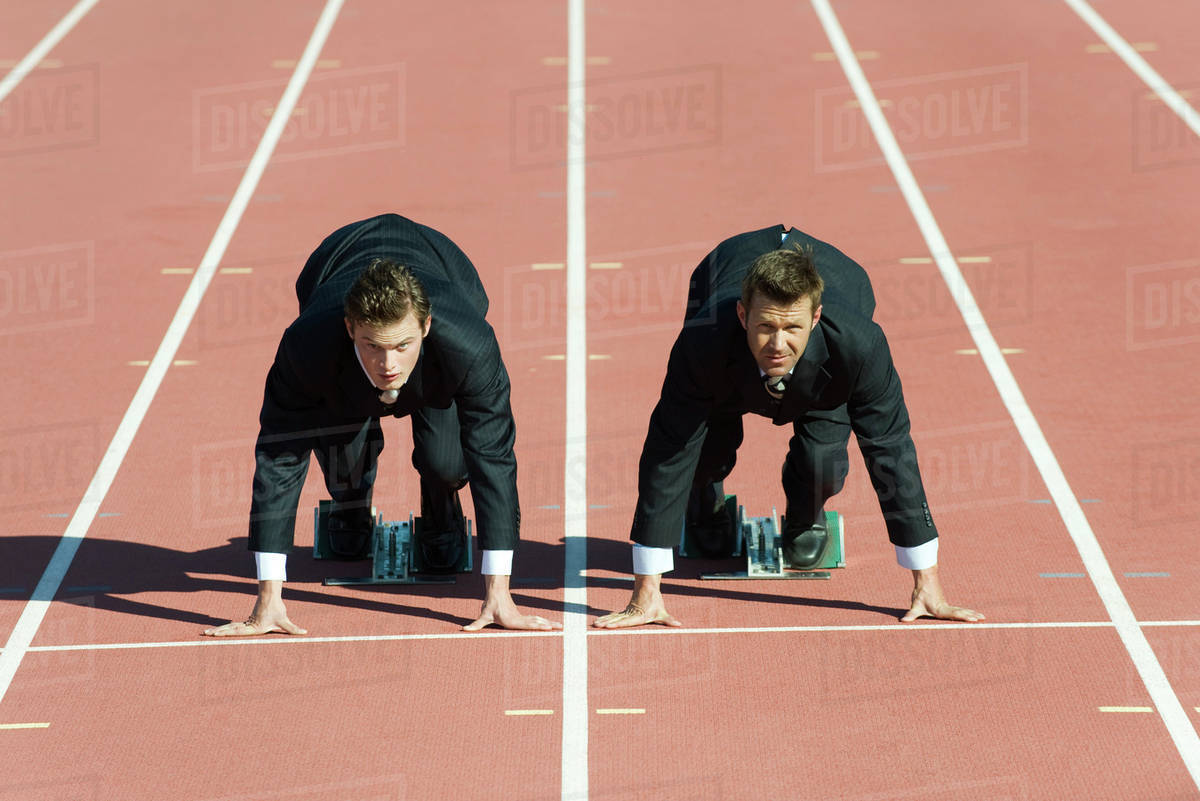 Businessmen crouched in starting position on running track - Royalty ...