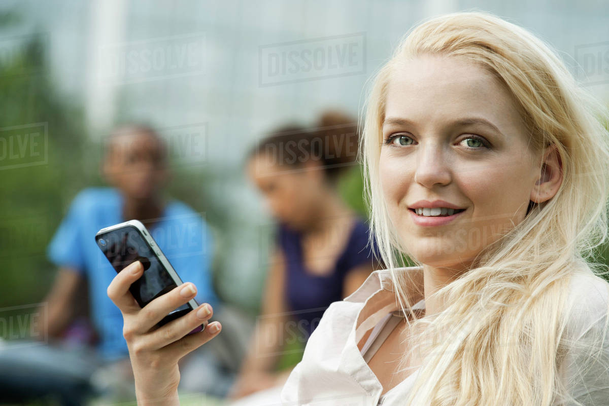 Young woman with cell phone, people in background, portrait - Royalty ...