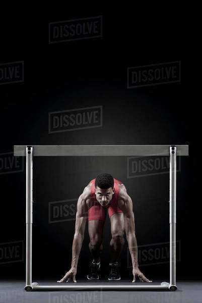 Male athlete at starting position in front of hurdle - Royalty-free ...